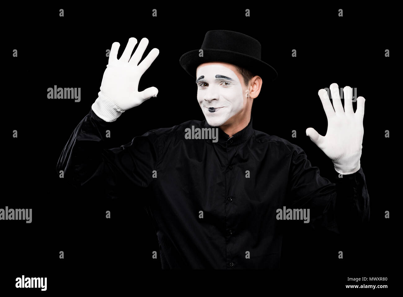smiling mime performing and touching something isolated on black Stock ...