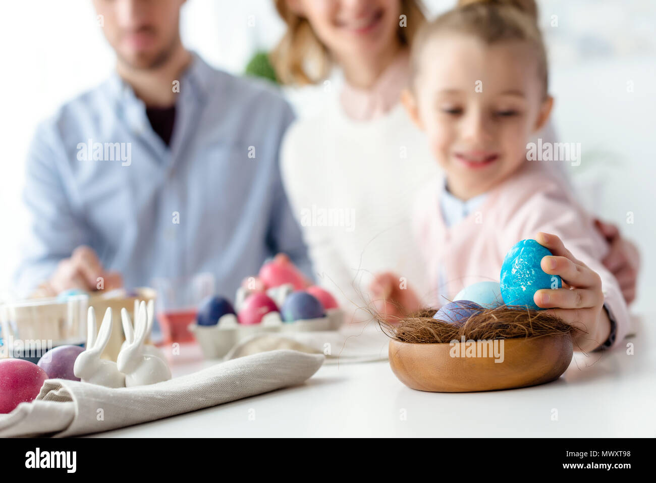 Child putting Easter egg in nest by her family Stock Photo - Alamy