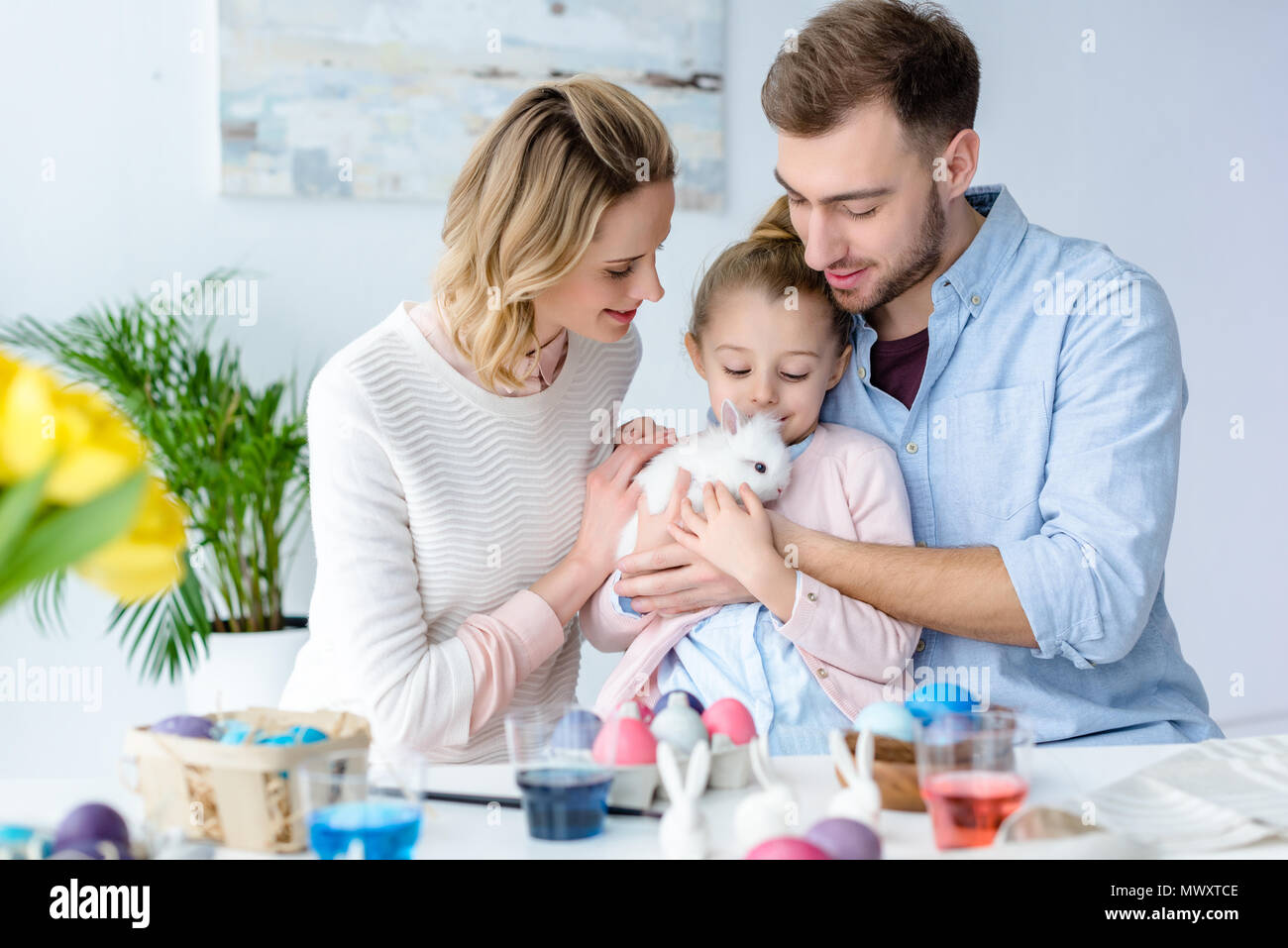 Family celebrating Easter with white bunny and painted eggs Stock Photo ...