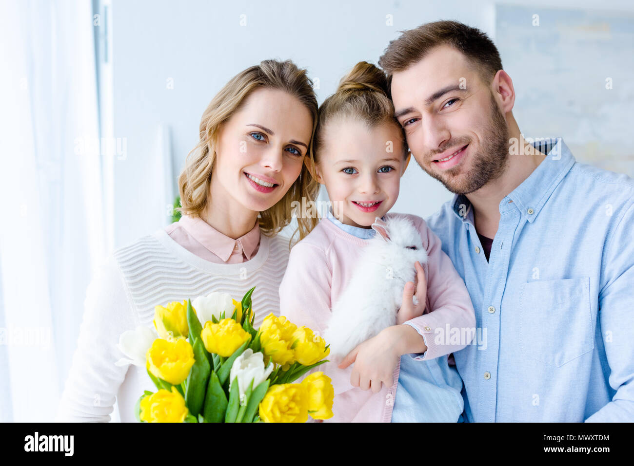 Smiling family with cute bunny looking at camera Stock Photo - Alamy