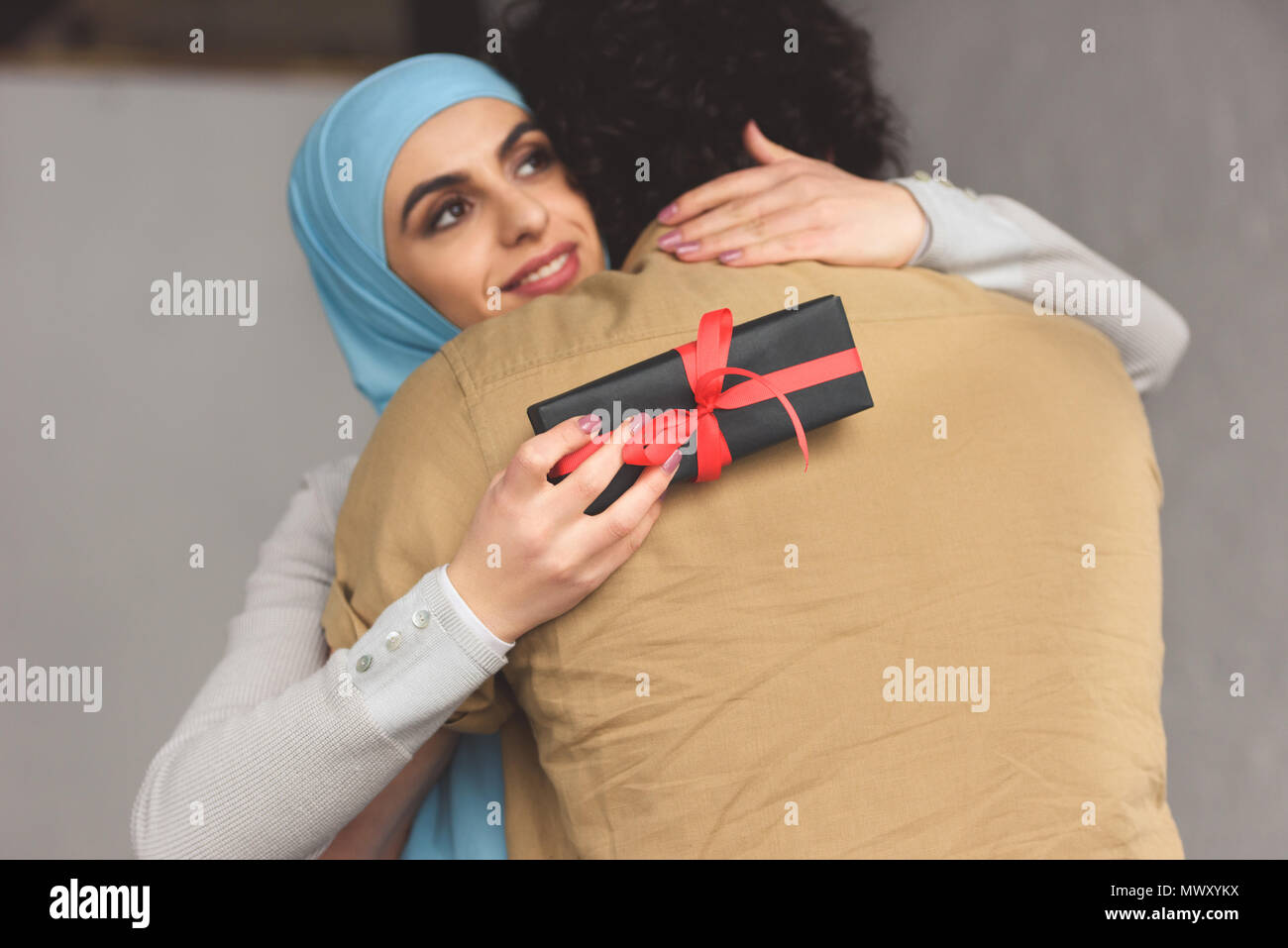 muslim girlfriend in hijab holding present box and hugging boyfriend at ...