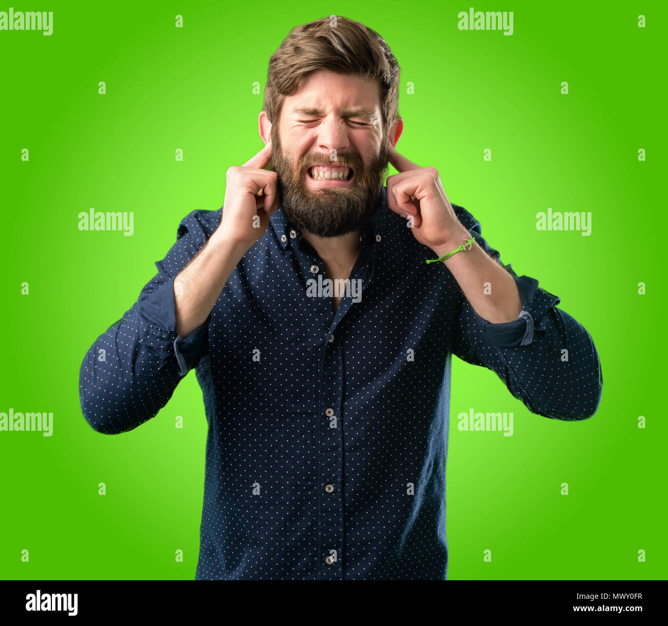Young hipster man with big beard covering ears ignoring annoying loud ...