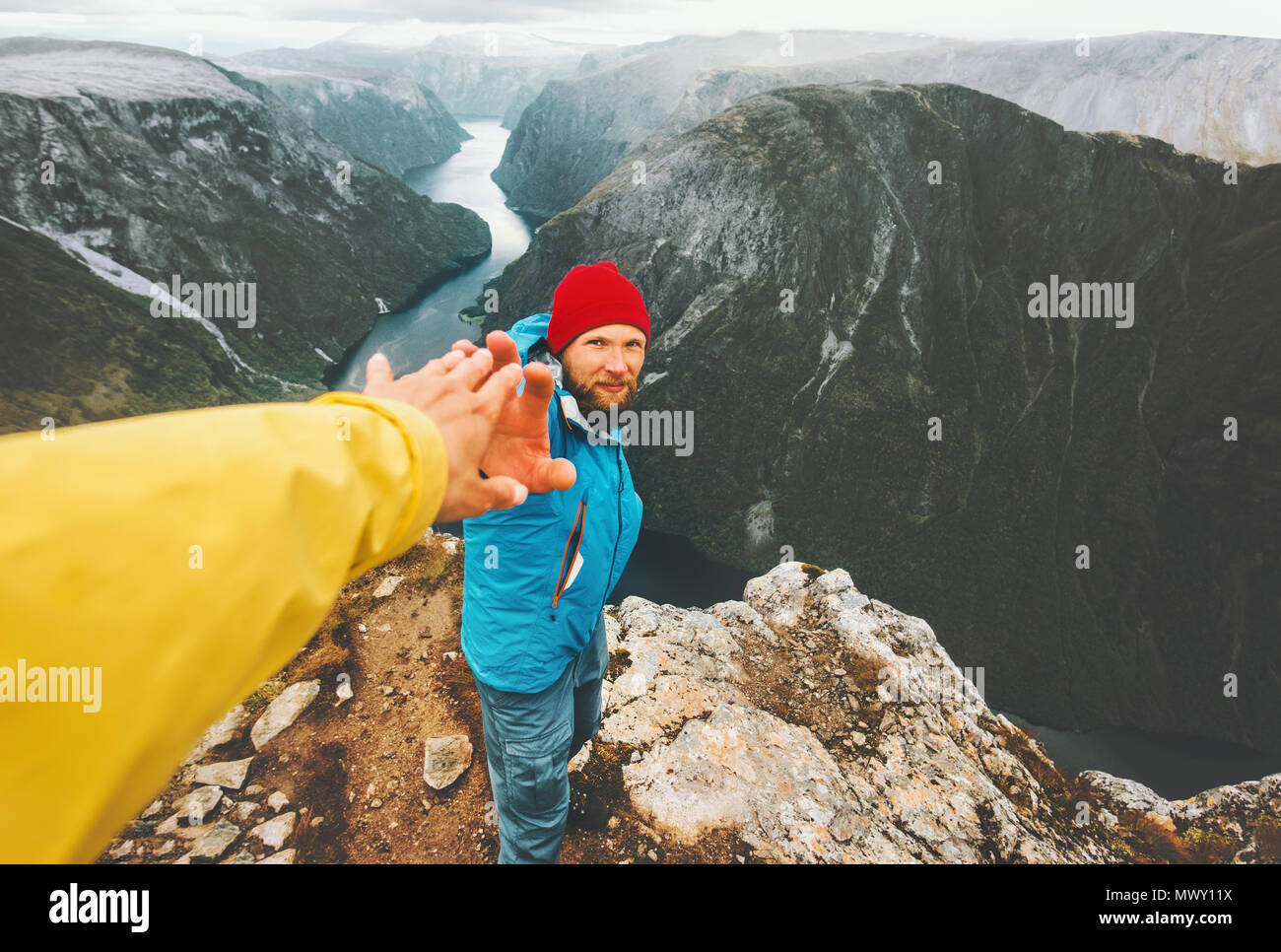 Couple adventurers in mountains follow helping hand traveling together ...