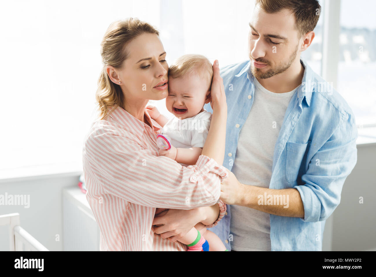 Parents trying to calm down crying infant daughter Stock Photo - Alamy