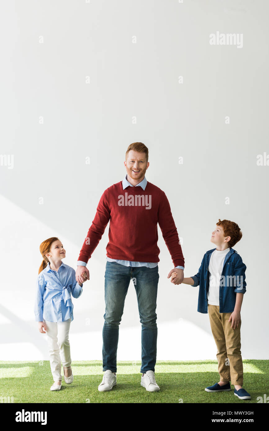 happy father with adorable smiling kids holding hands while standing on ...