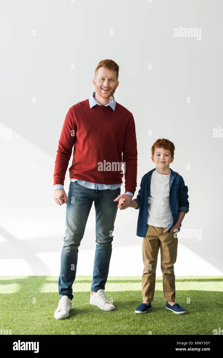 full length view of happy redhead father and son holding hands and ...