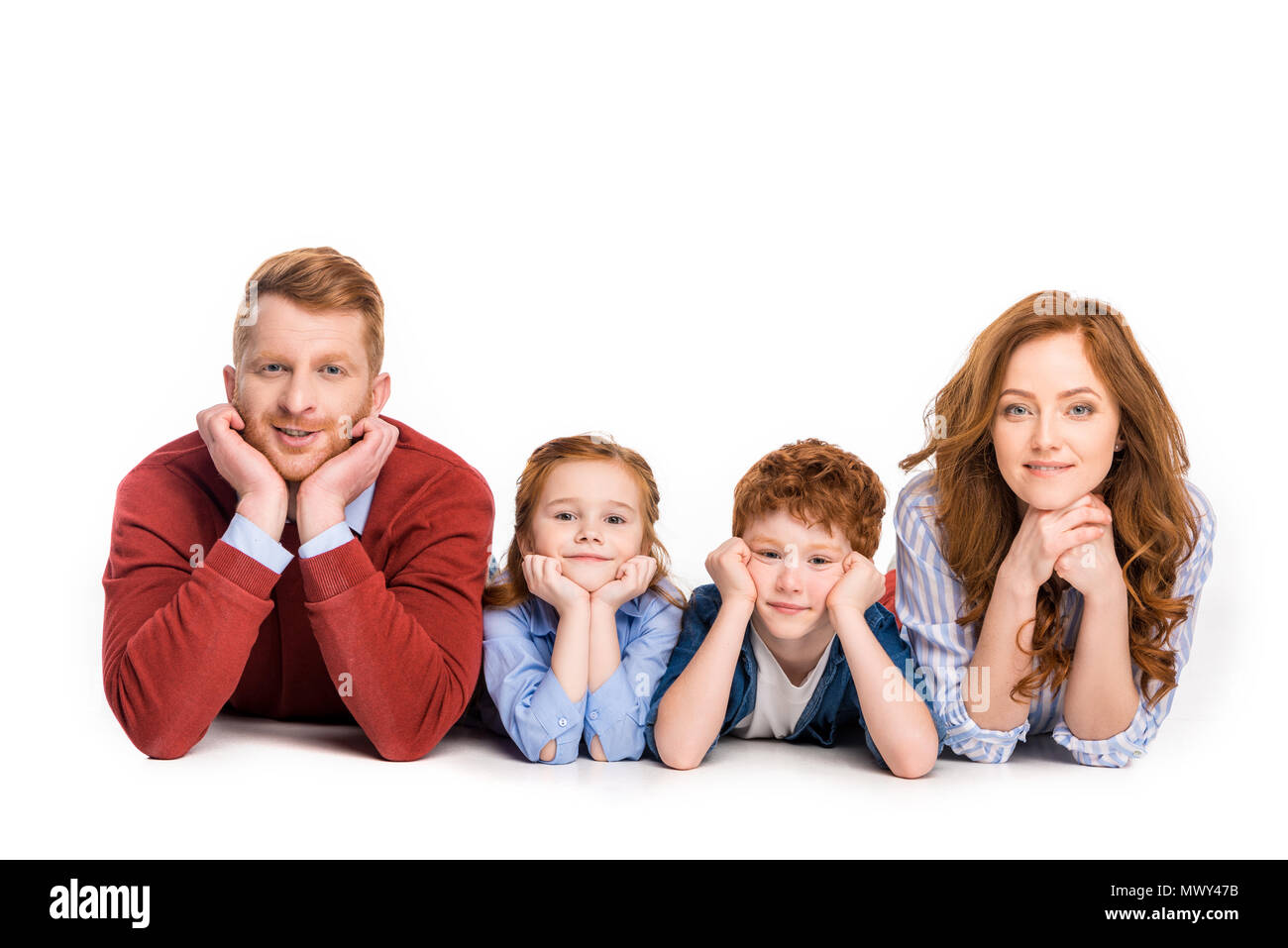 happy redhead family lying together and smiling at camera isolated on ...