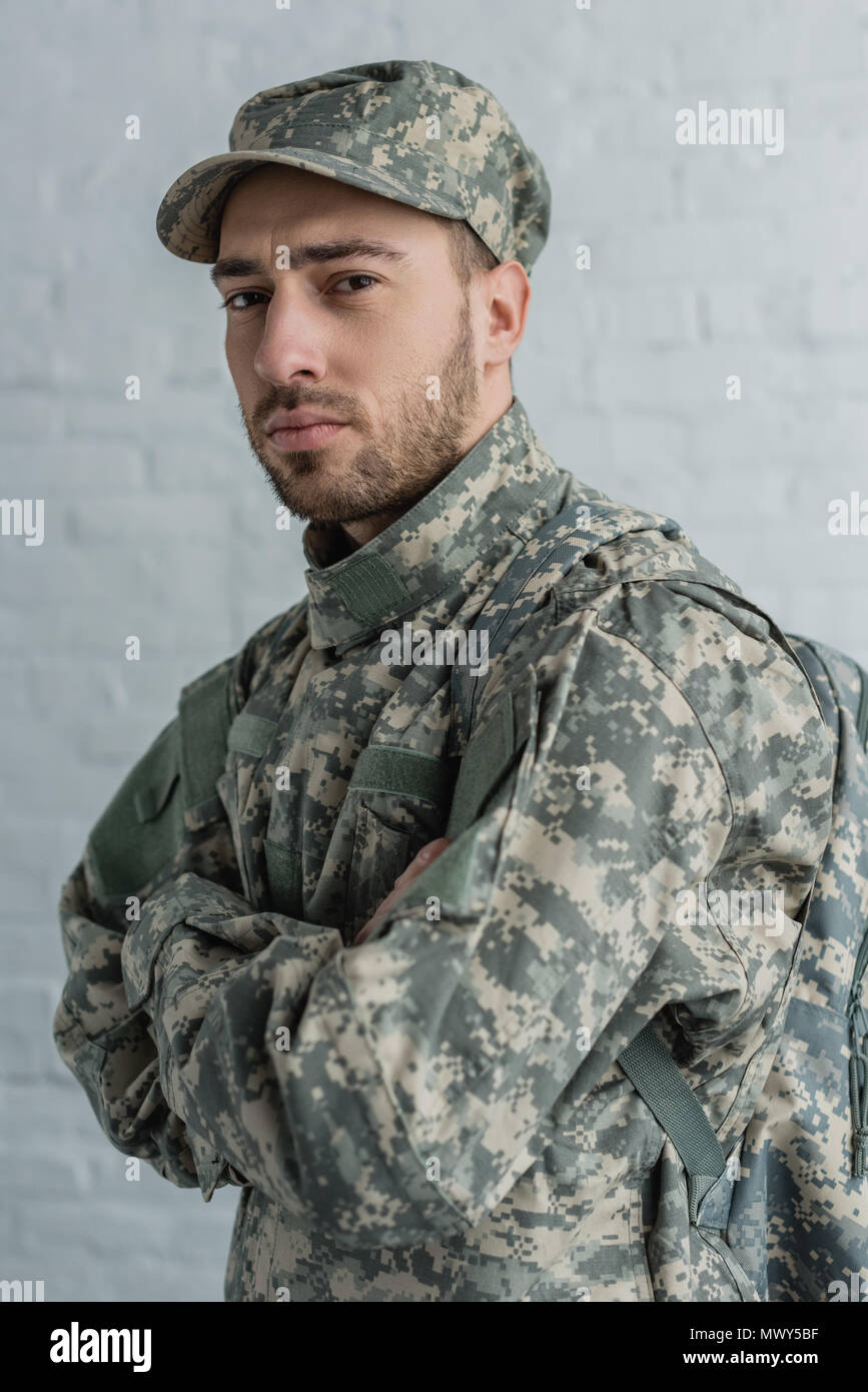 portrait of soldier in military uniform looking at camera against white ...