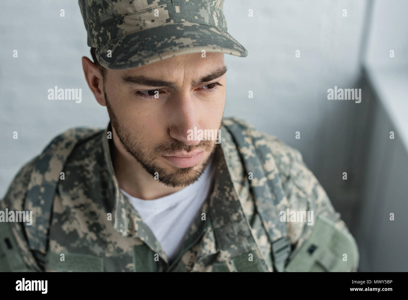 portrait of soldier in military uniform looking away against white ...