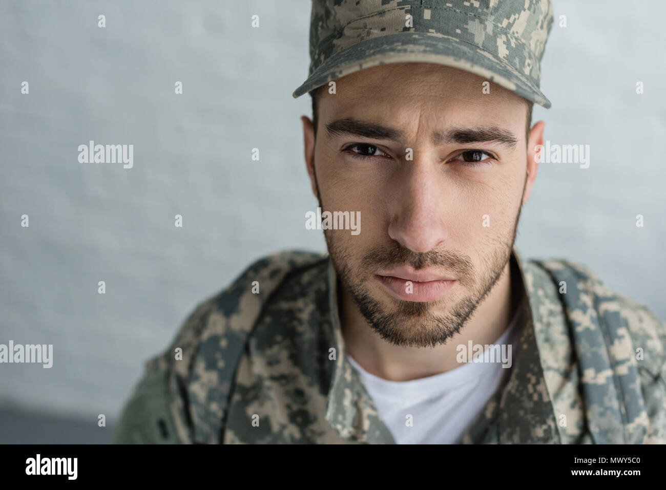 portrait of soldier in military uniform looking at camera against white ...