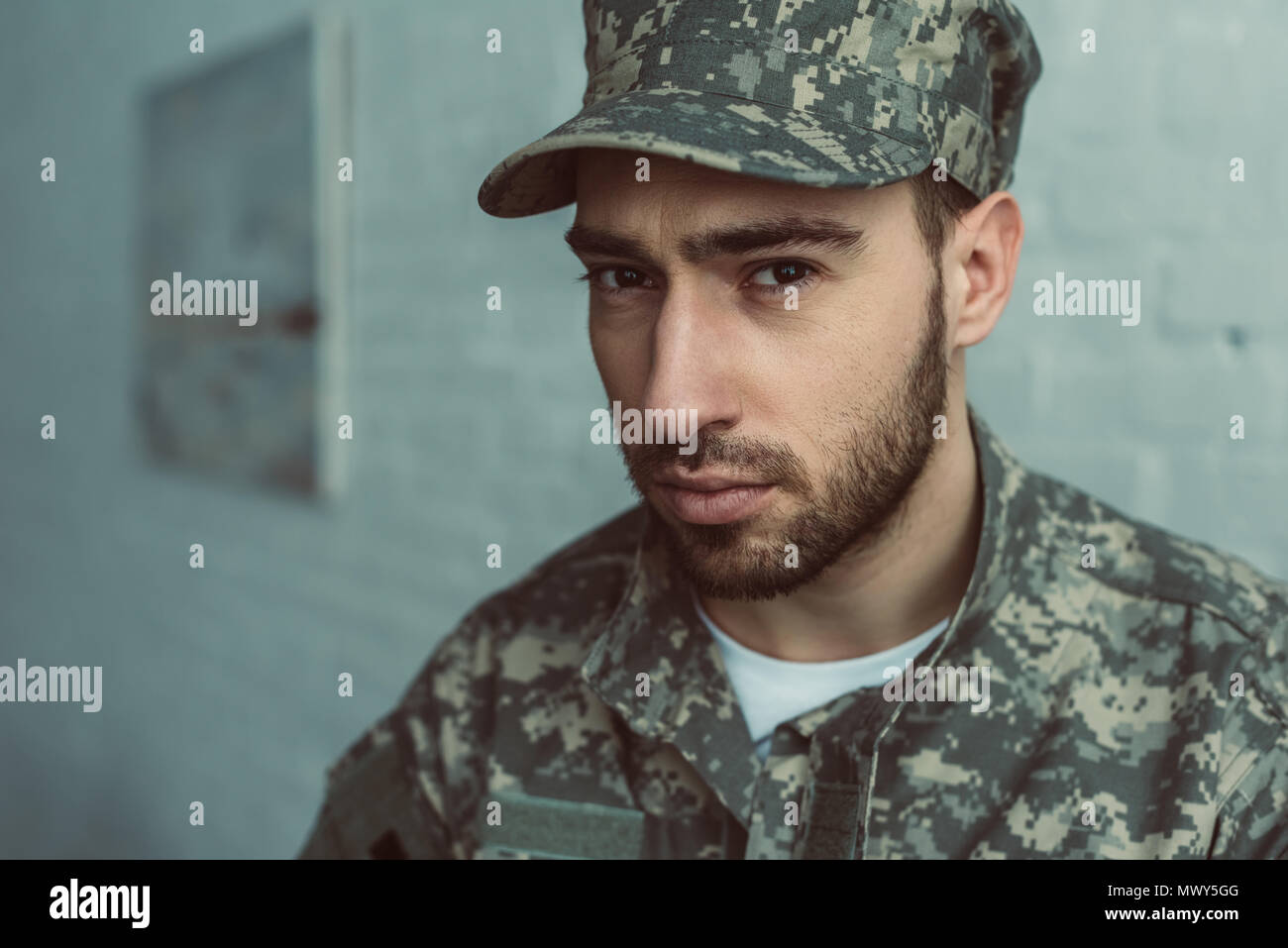 portrait of soldier in military uniform looking at camera against white ...