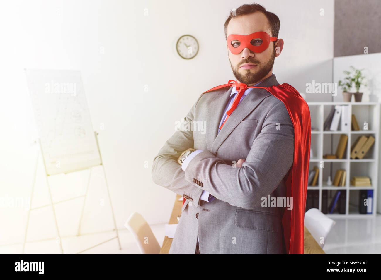 serious super businessman in mask and cape standing with crossed arms ...