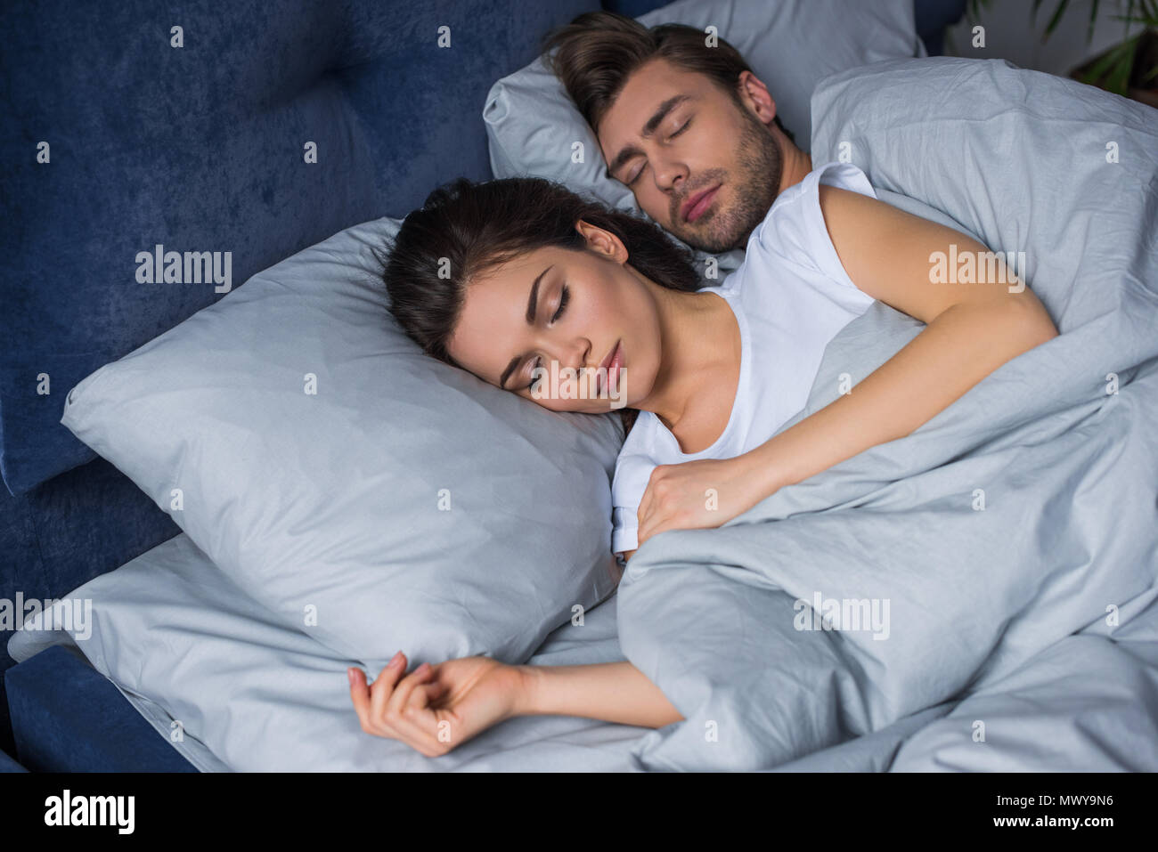 Young attractive couple hugging while sleeping in bed Stock Photo - Alamy