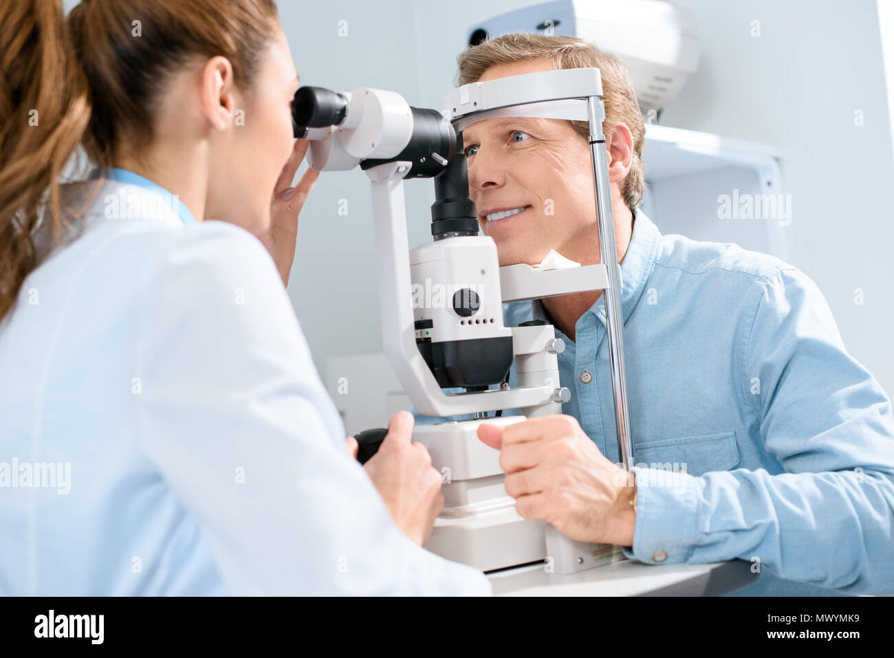 professional female optician examining man with modern visual equipment Stock Photo - Alamy