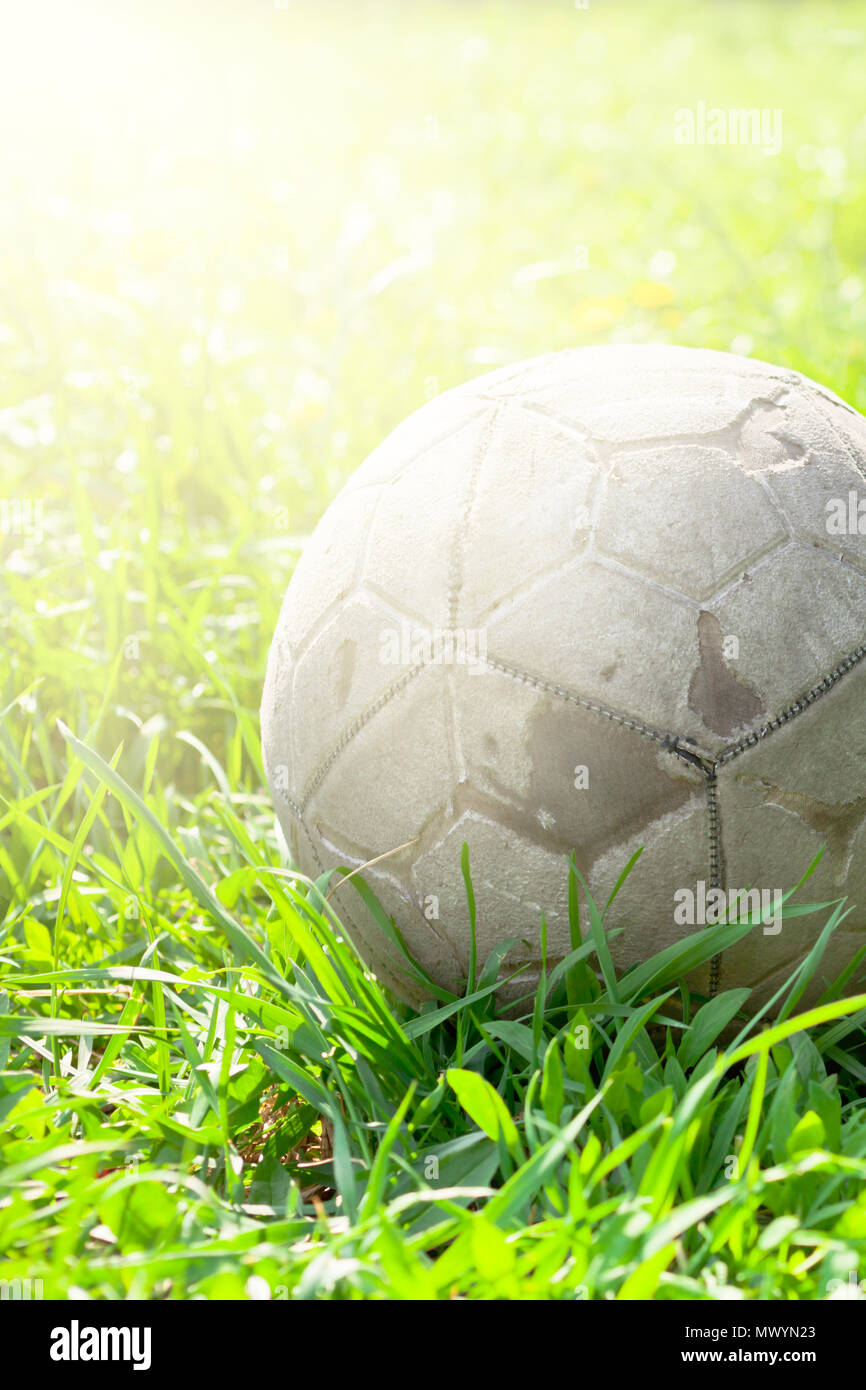 Old soccer ball forgotten in the green grass field. The football ...