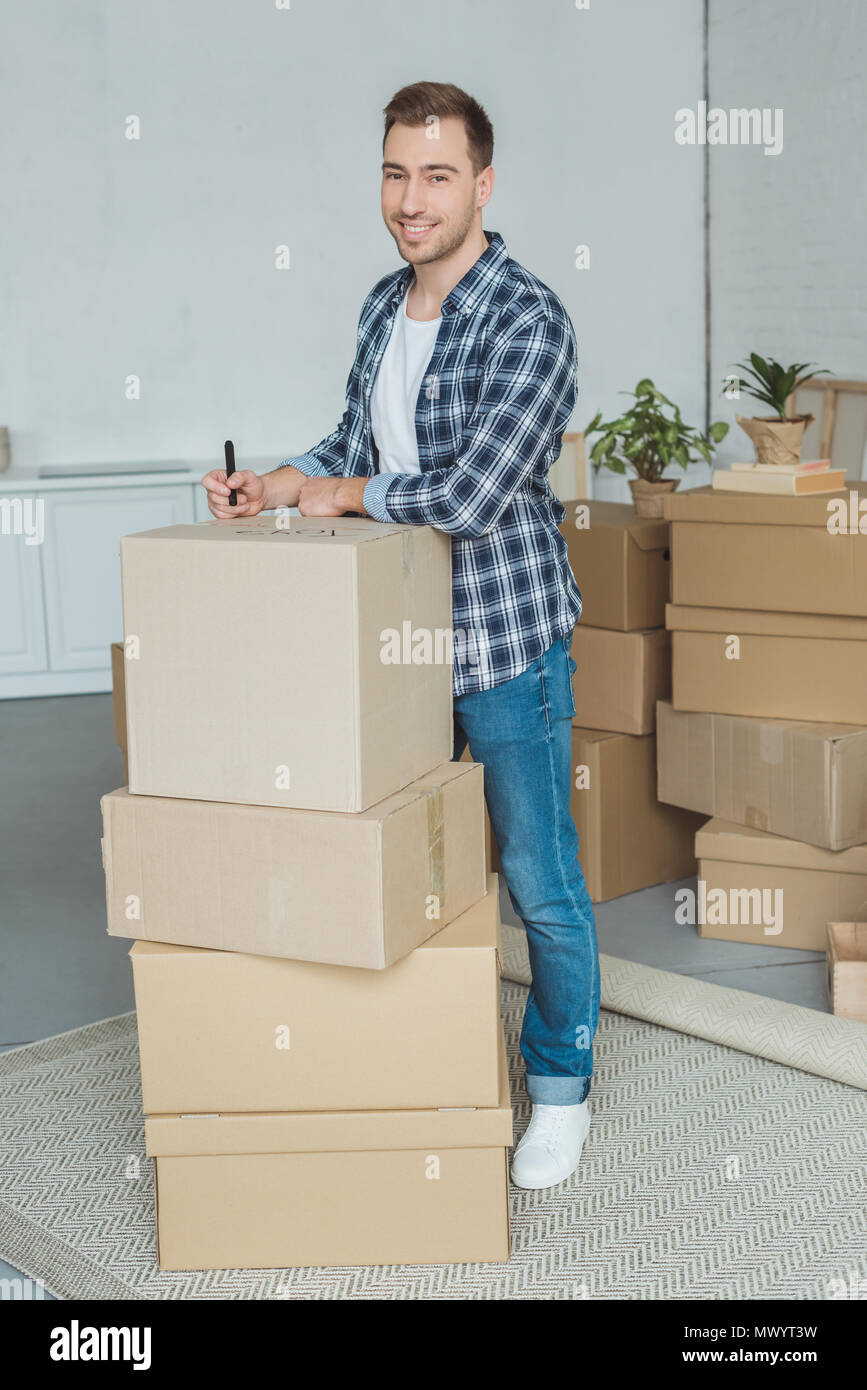 smiling man signing cardboard box for moving home, relocation concept ...