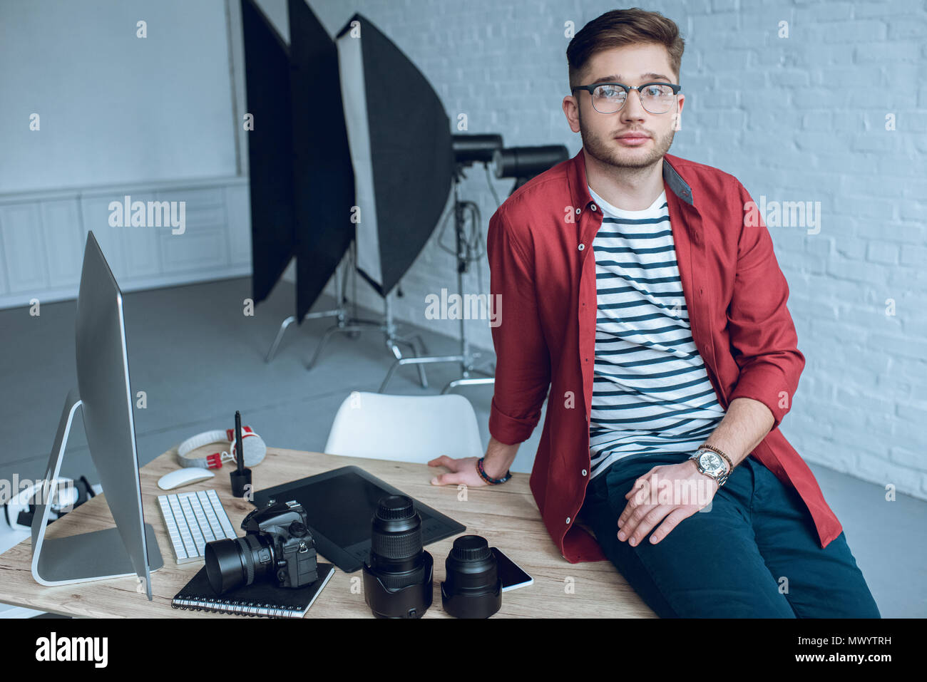 Young photographer sitting on table with camera and computer Stock ...