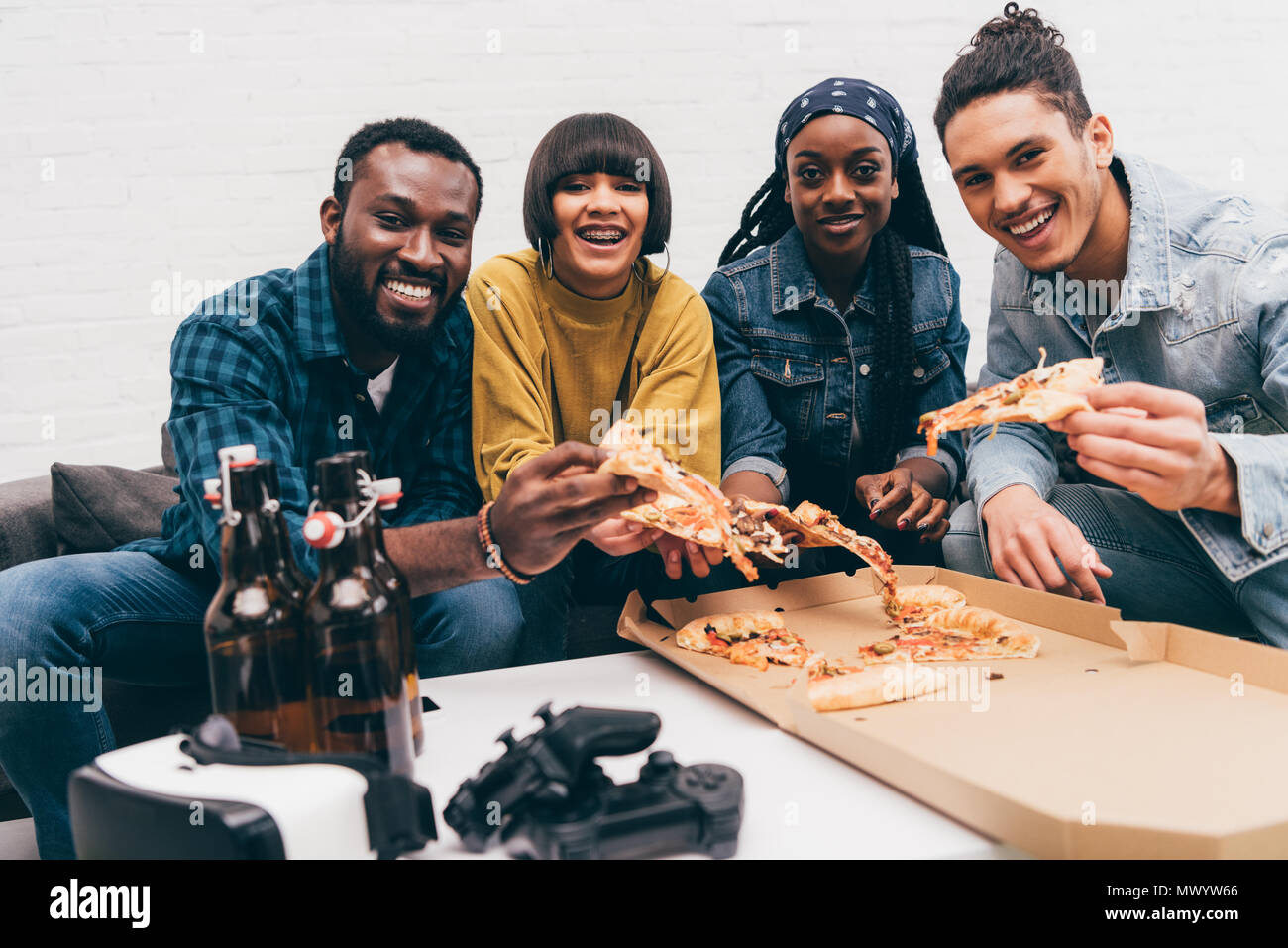 smiling group of young multicultural friends eating pizza Stock Photo ...