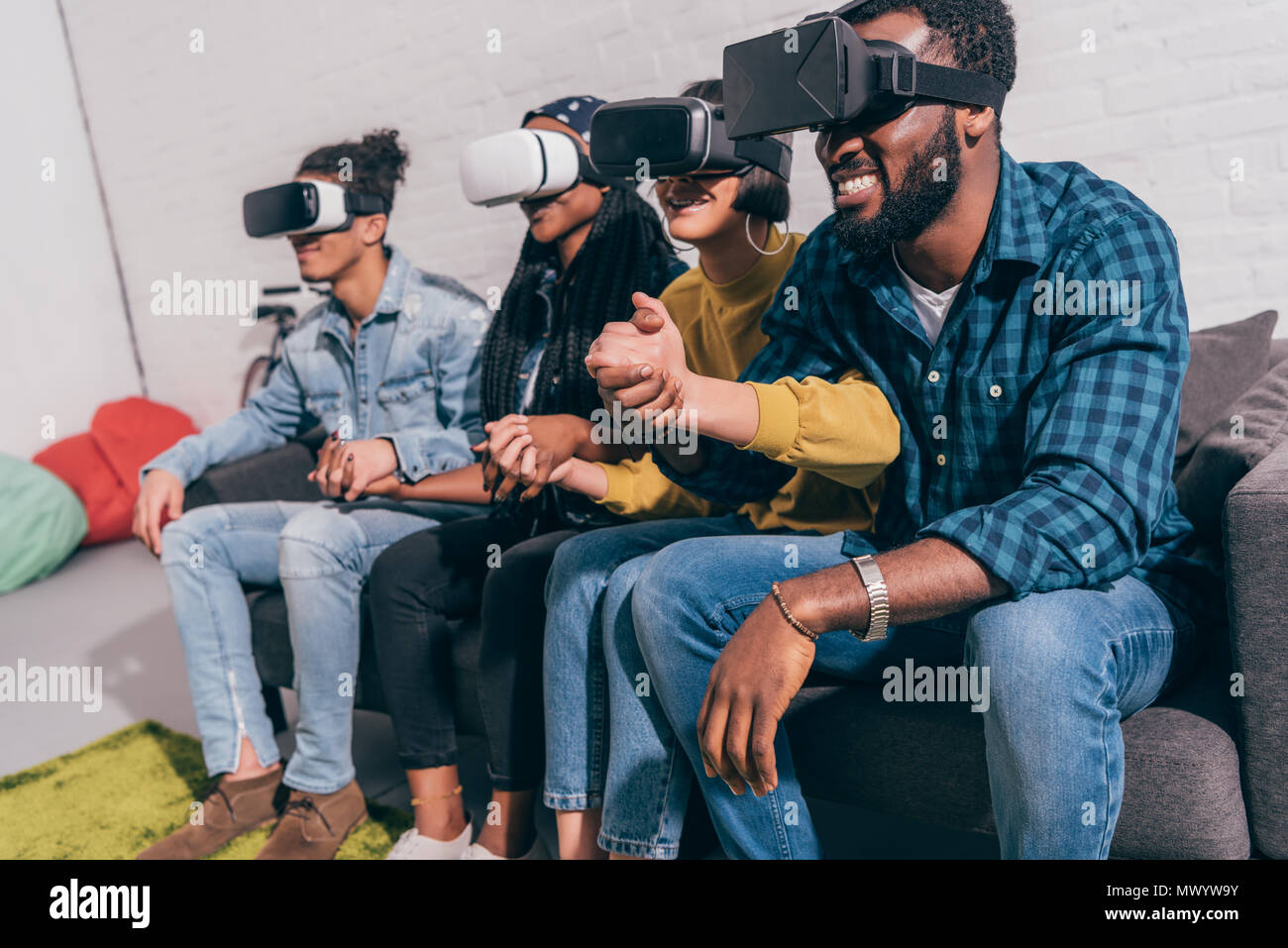 young multicultural friends using virtual reality headsets and holding ...