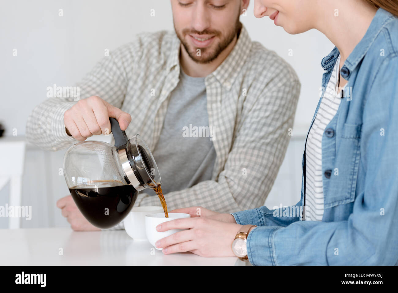 husband pouring coffee from pot into cups on kitchen with wife Stock ...