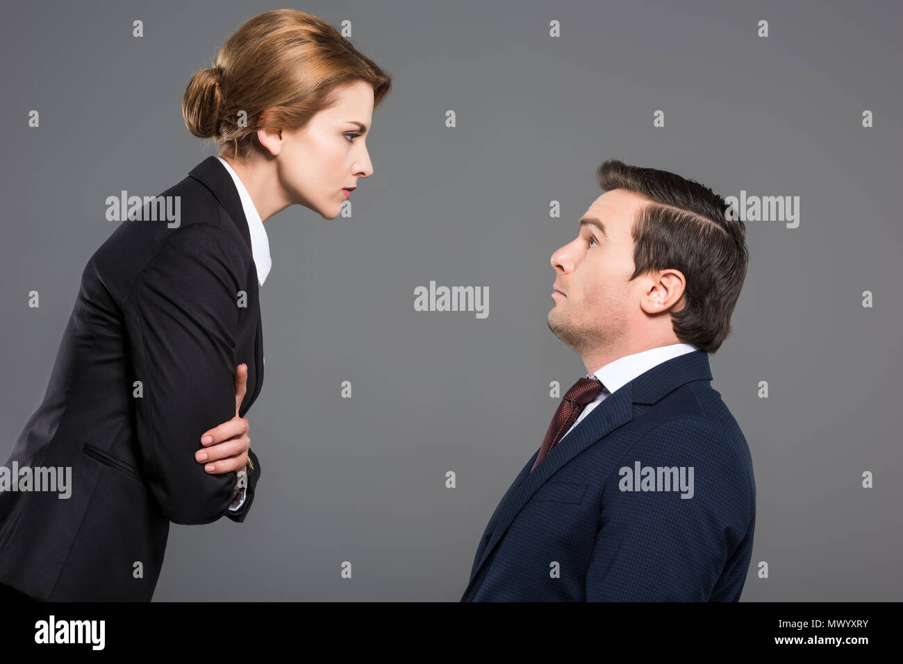 angry female boss looking at scared businessman, isolated on grey ...