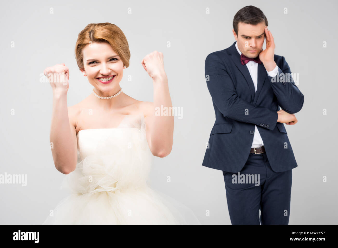 excited bride in wedding dress and worried groom behind, isolated on ...