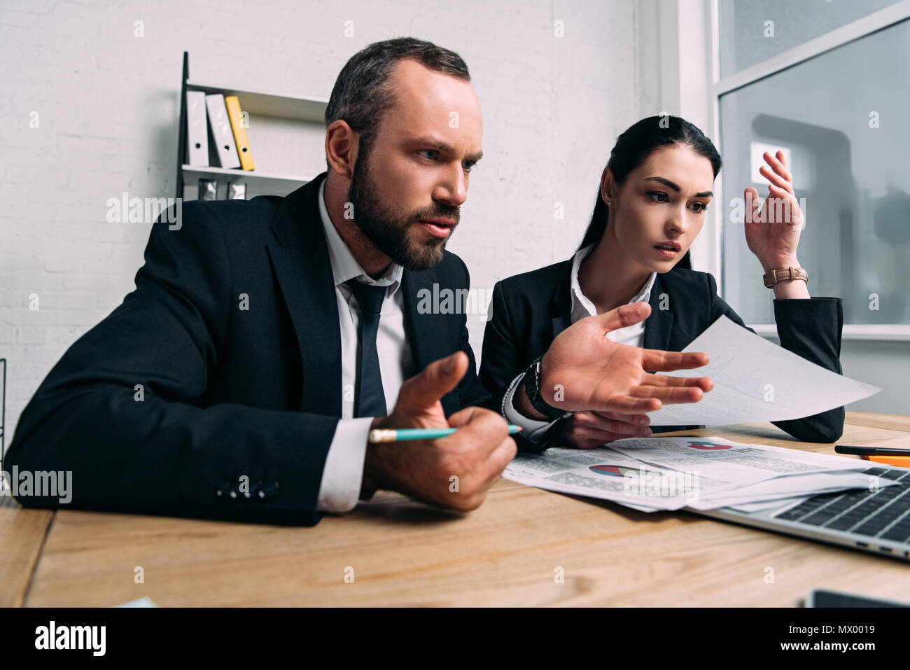 side view of stressed business people at workplace with laptop in ...