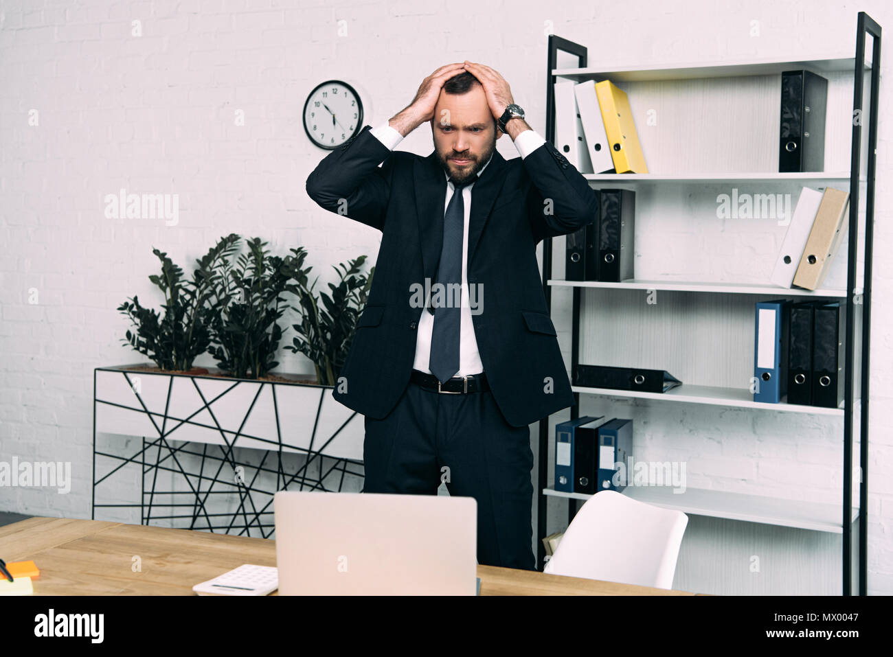 portrait of stressed businessman in suit standing at workplace in ...