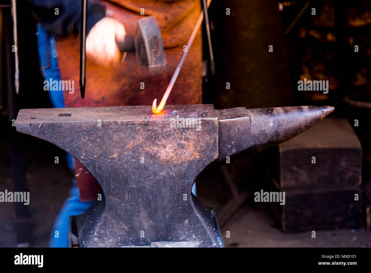 Blacksmith at work at the anvil in the old smithy at Cockington Forge ...