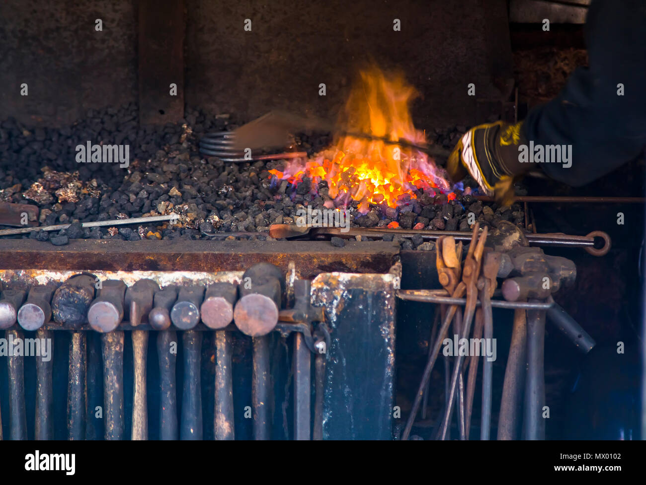 Blacksmith at work at the anvil in the old smithy at Cockington Forge ...