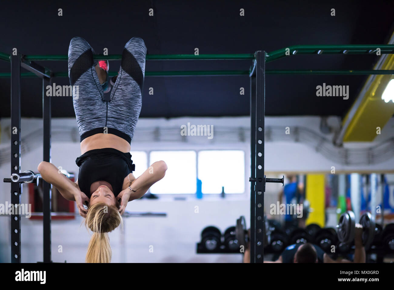 athlete woman doing abs exercises hanging upside down on horizontal bar ...