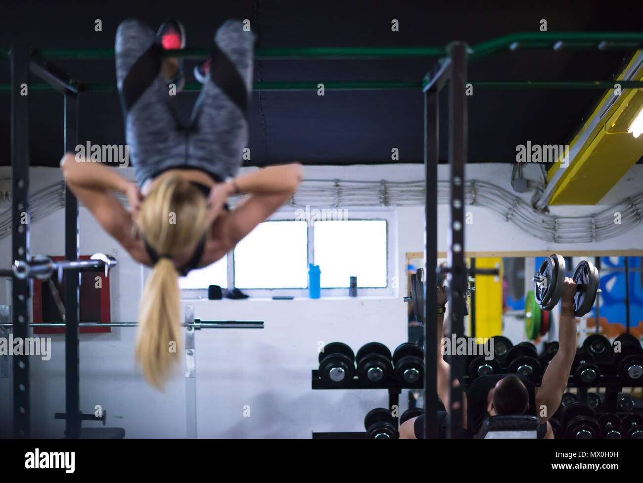 athlete woman doing abs exercises hanging upside down on horizontal bar ...