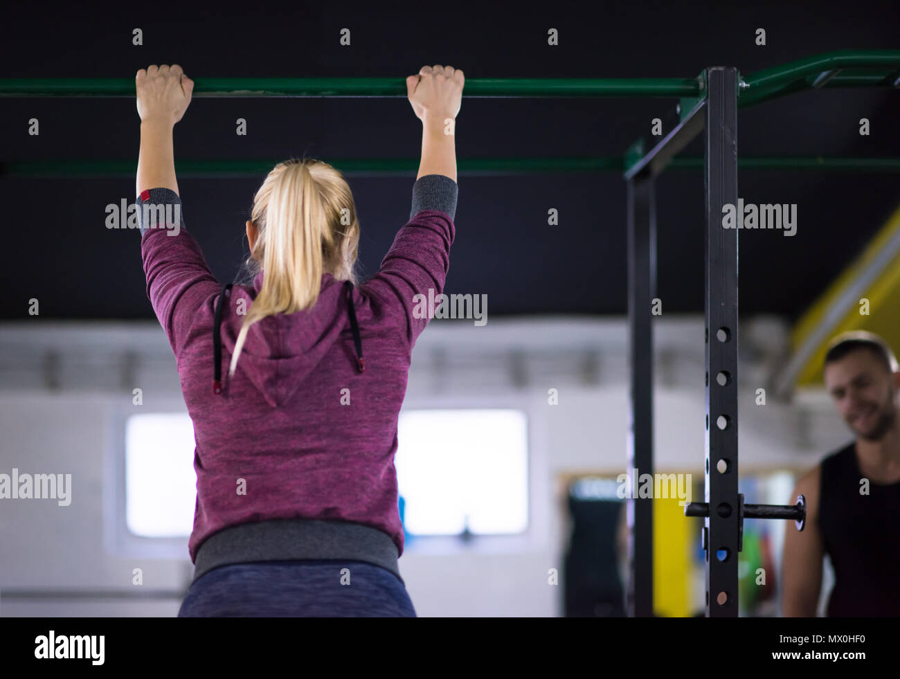 young muscular woman doing pull ups on the horizontal bar as part of Cross fitness Training ...