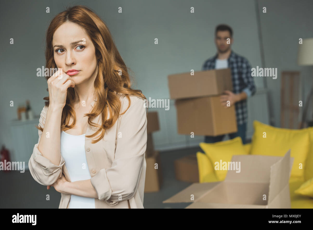 serious young woman standing with hand on chin while husband holding ...