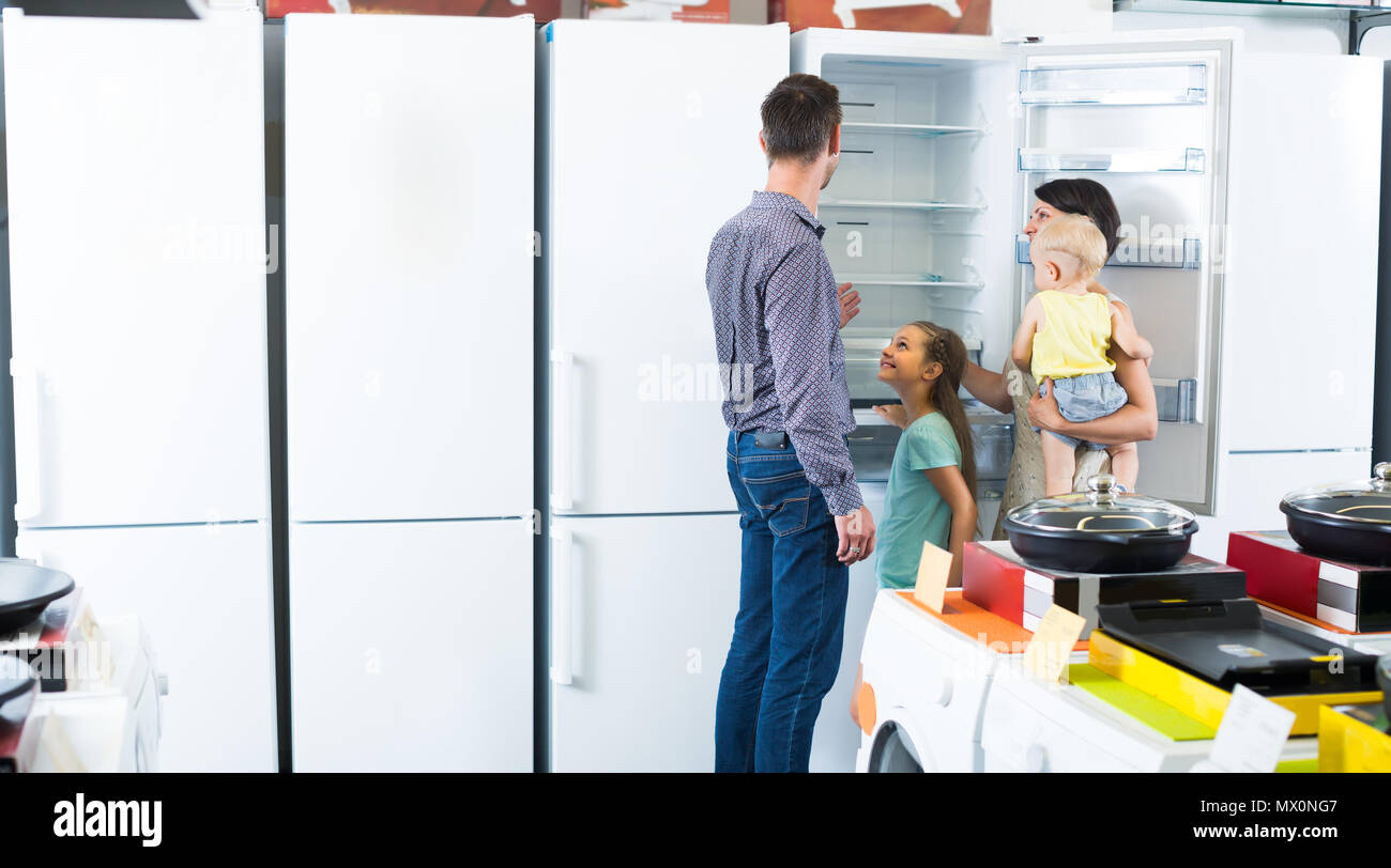 family with two kids choosing new freezer in household appliances store ...