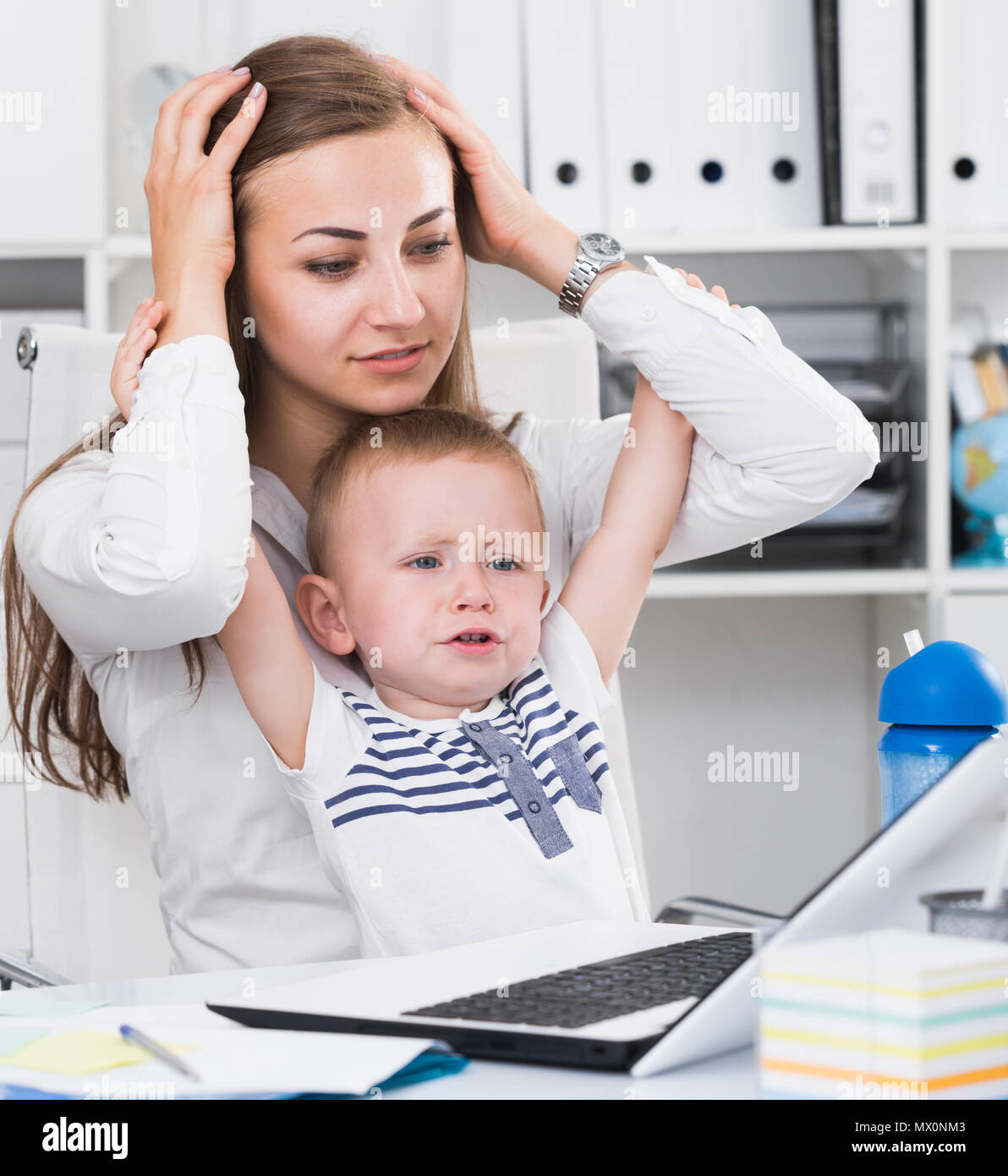 Perplexed female with kid is having issue while working behind laptop ...