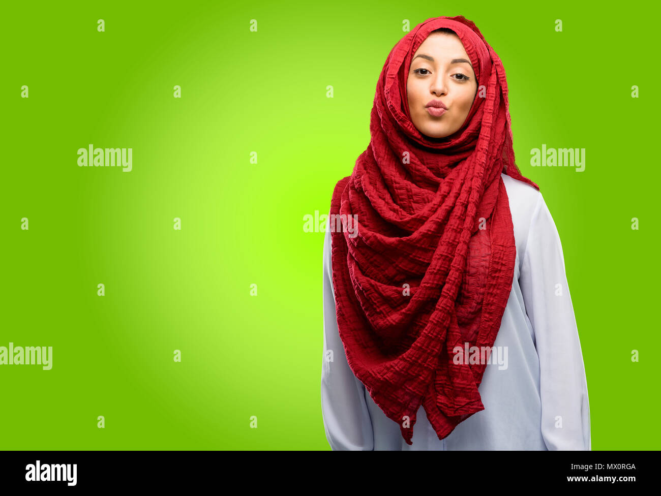 Young arab woman wearing hijab expressing love, blows kiss at camera ...