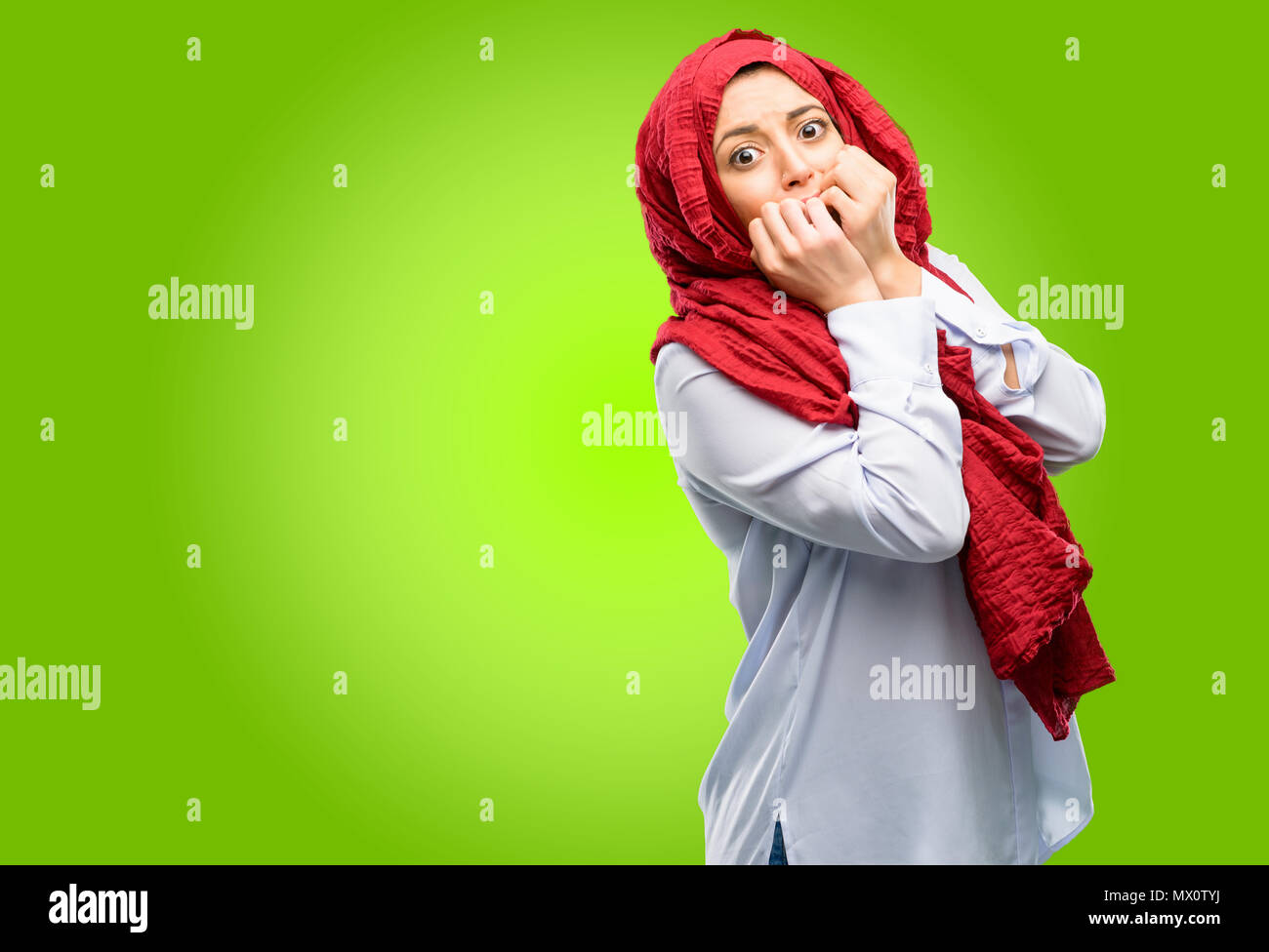 Young arab woman wearing hijab terrified and nervous expressing anxiety ...