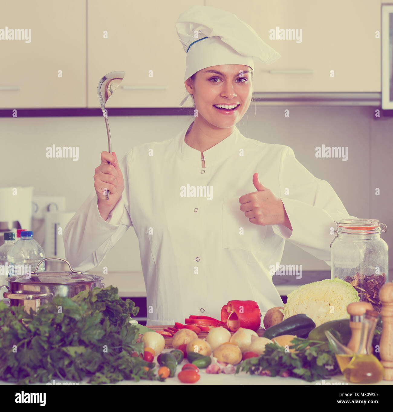Positive smiling girl in uniform cooking vegetables at kitchen Stock ...