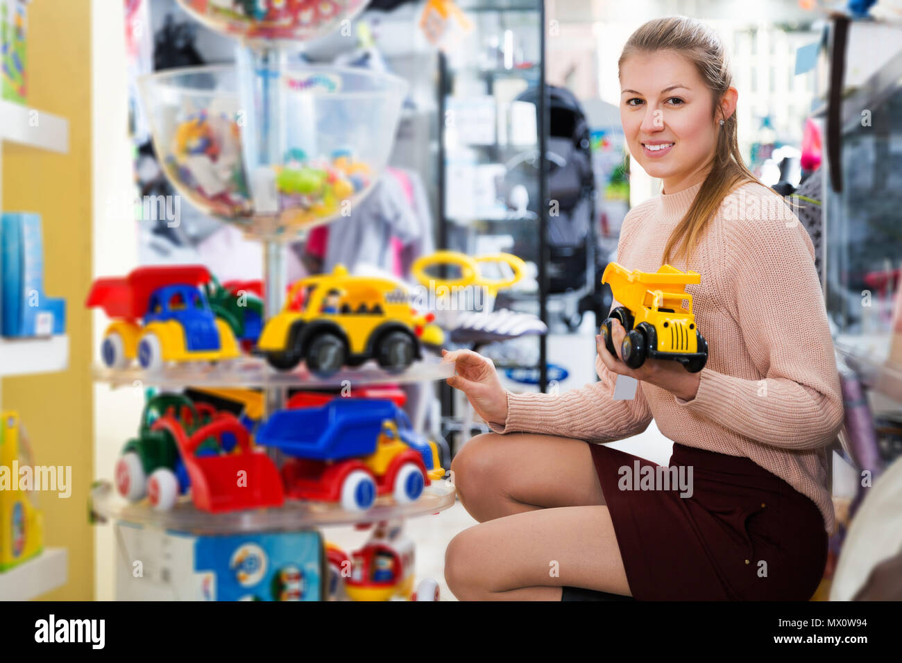Young female consumer with children's plastic toys in the kids store ...