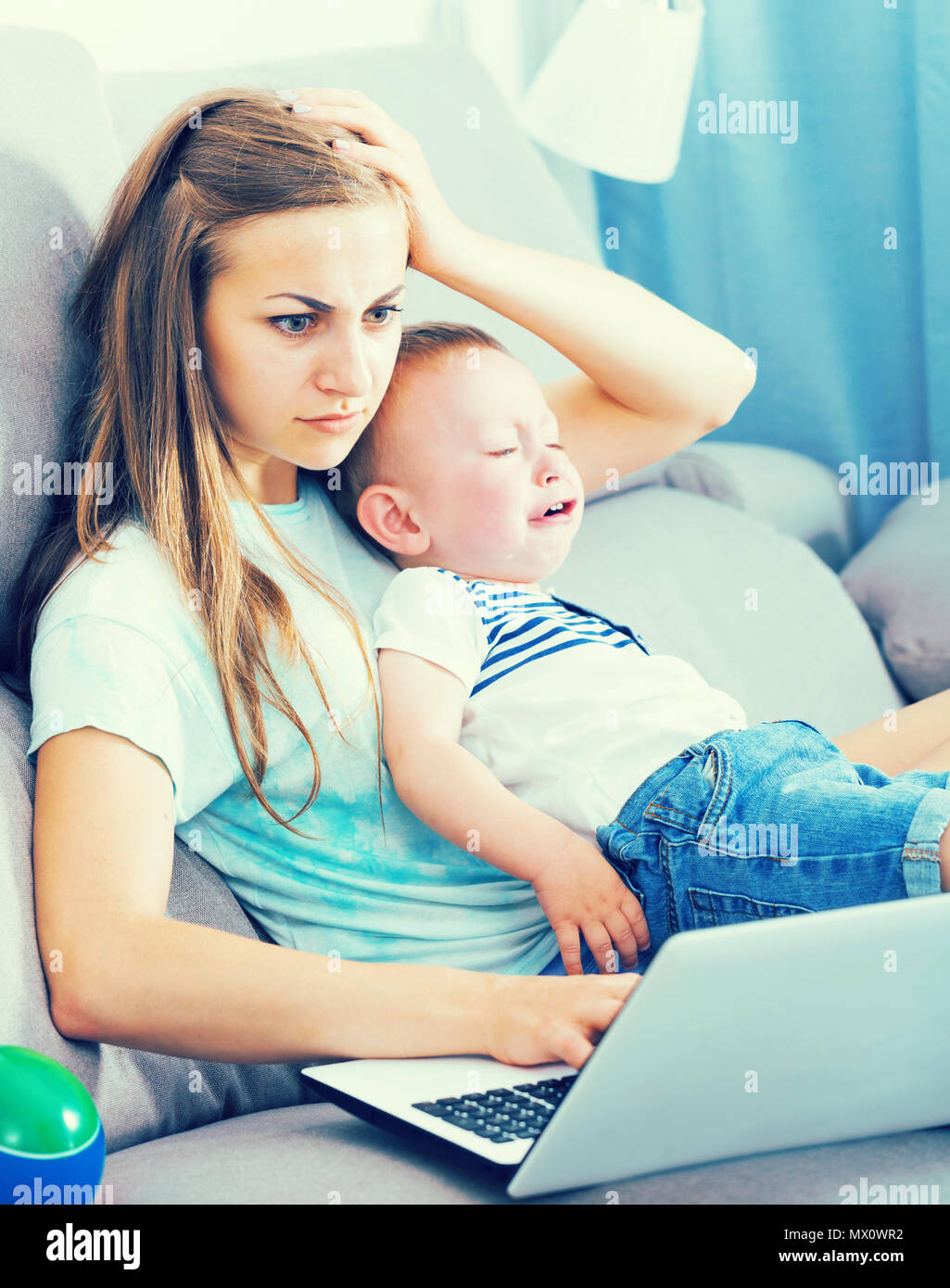 Perplexed girl is having issue with work while child crying at home ...