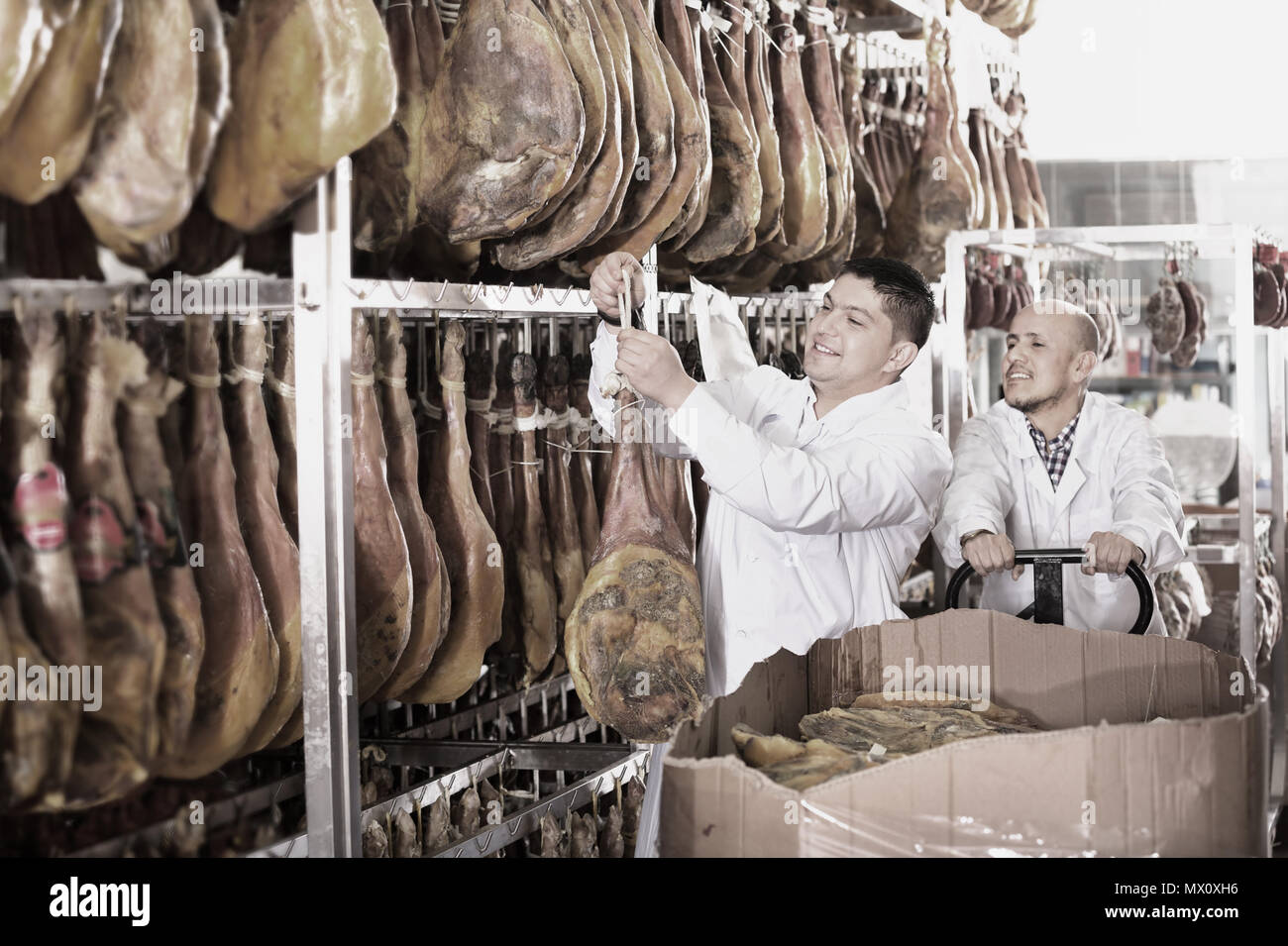 Mature butcher and his assistant with a jamon joints at meat factory ...