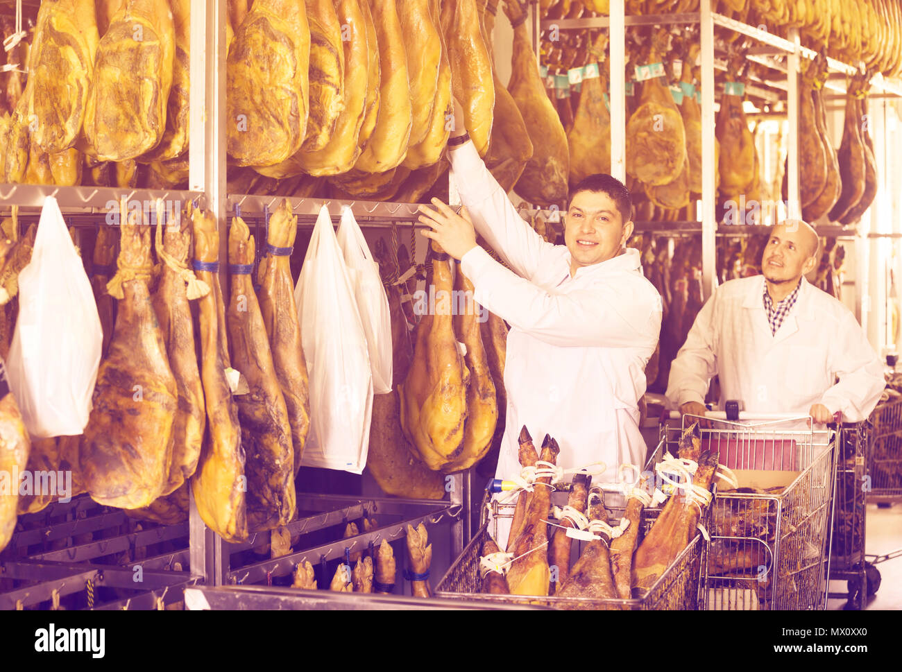 Mature butcher and his assistant with the jamon joints at a meat ...