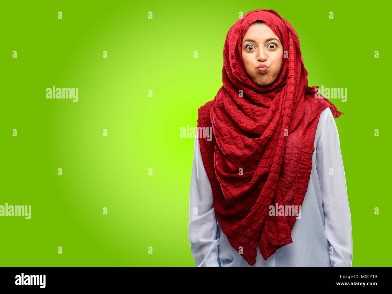 Young arab woman wearing hijab puffing out cheeks, having fun making ...