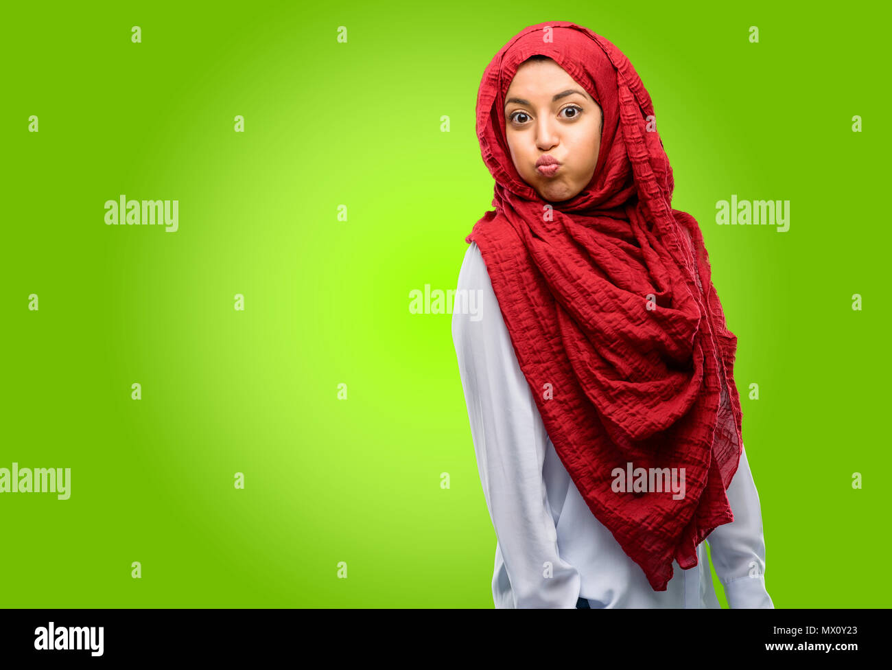 Young arab woman wearing hijab puffing out cheeks, having fun making ...