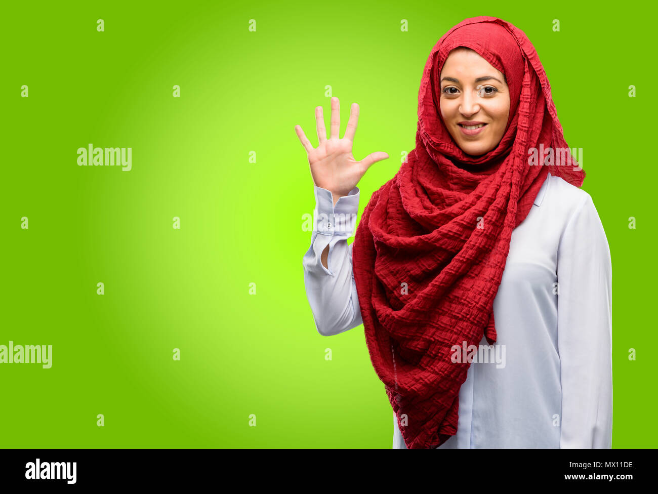 Young arab woman wearing hijab raising his finger, is the number five ...