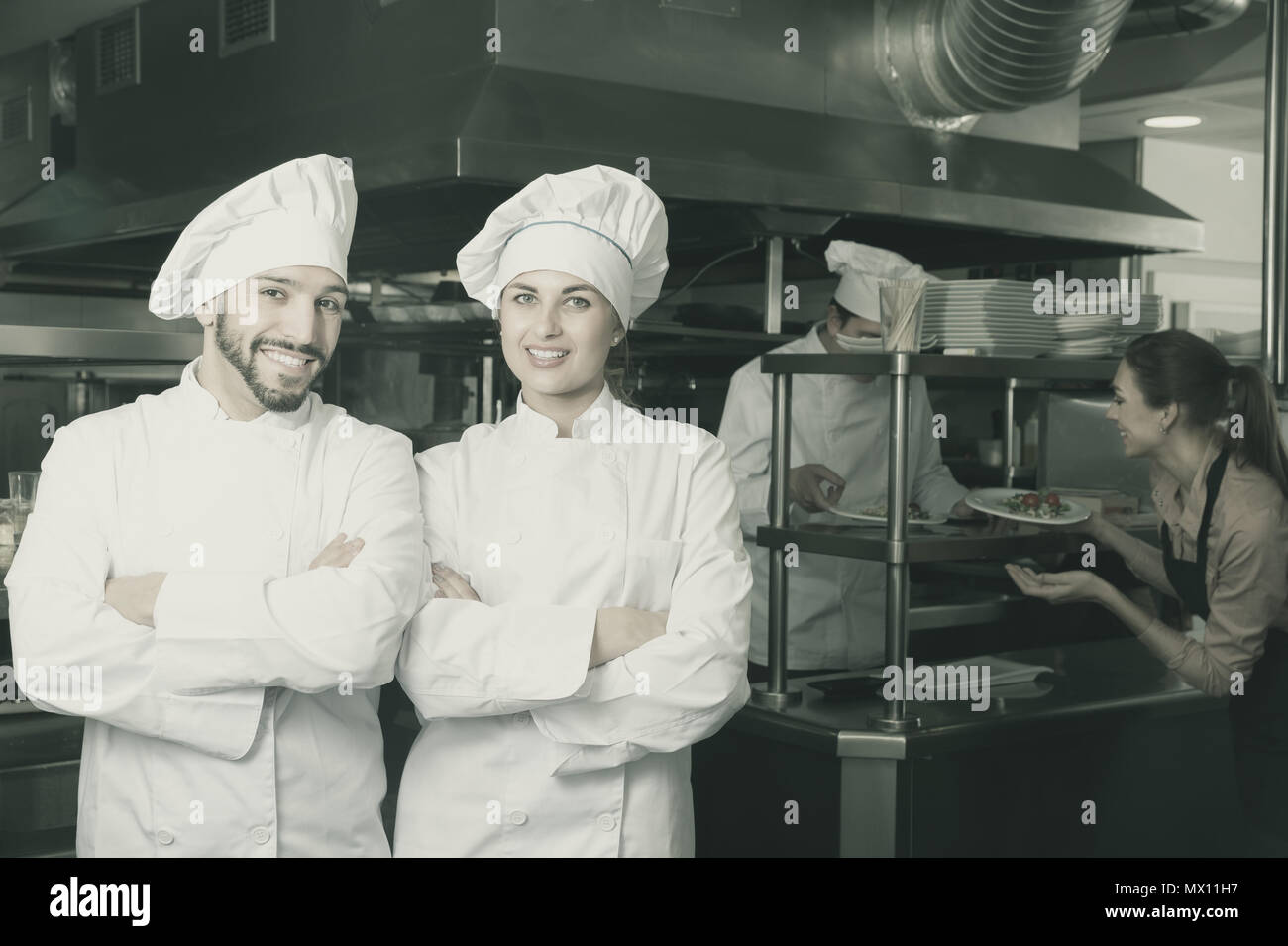 Portrait of two positive confident chefs posing with crossed arms in ...