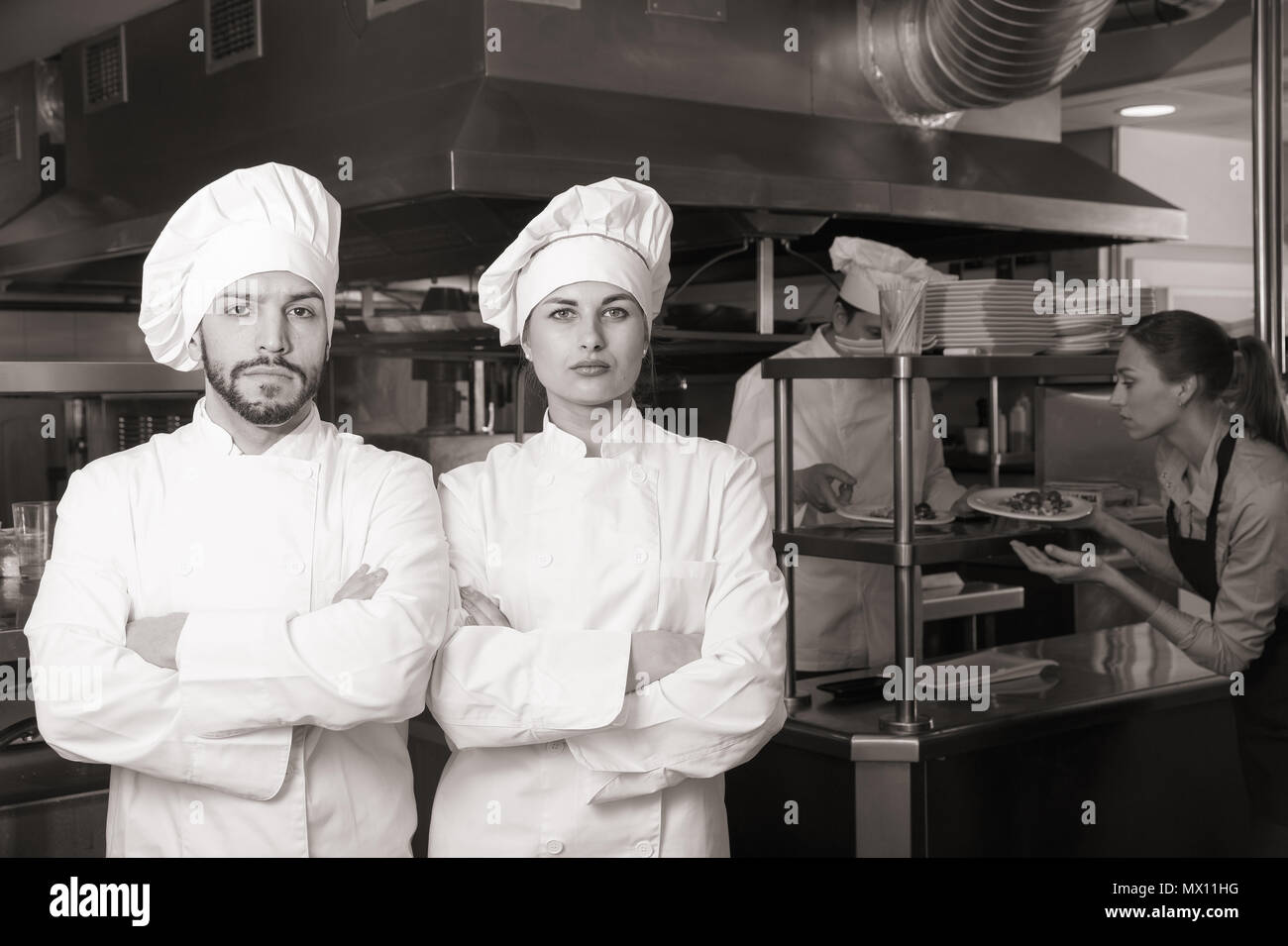 Portrait of two confident chefs posing with crossed arms in ...