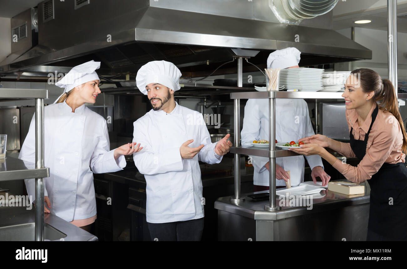 Staff of restaurant with nice head chef working together in kitchen ...