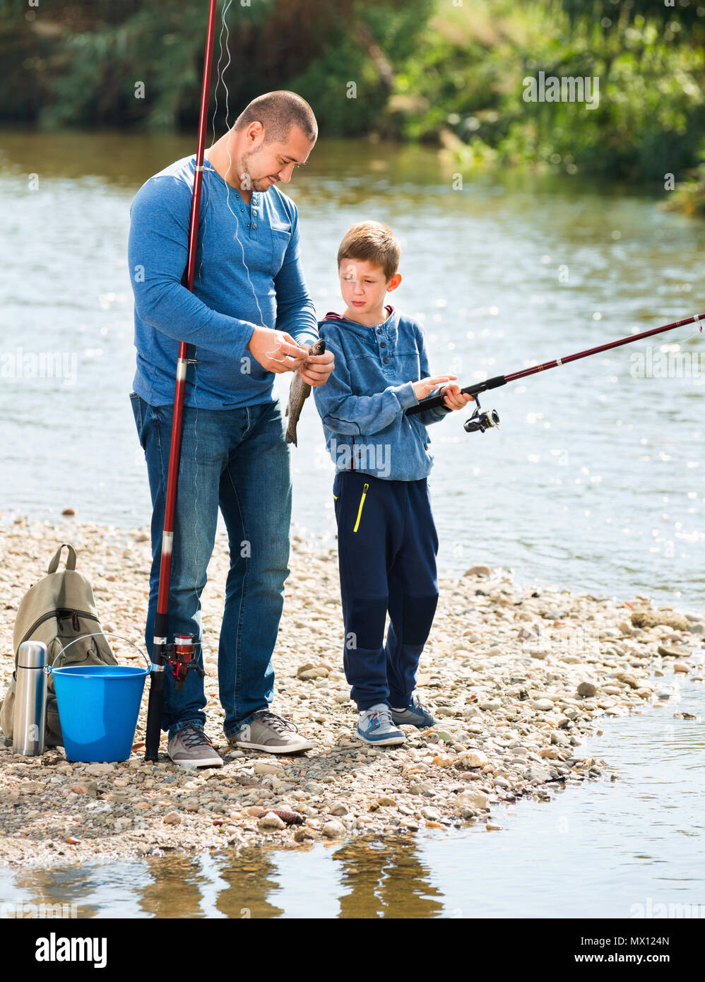 Portrait of happy smiling father and cute son fishing with rods in ...